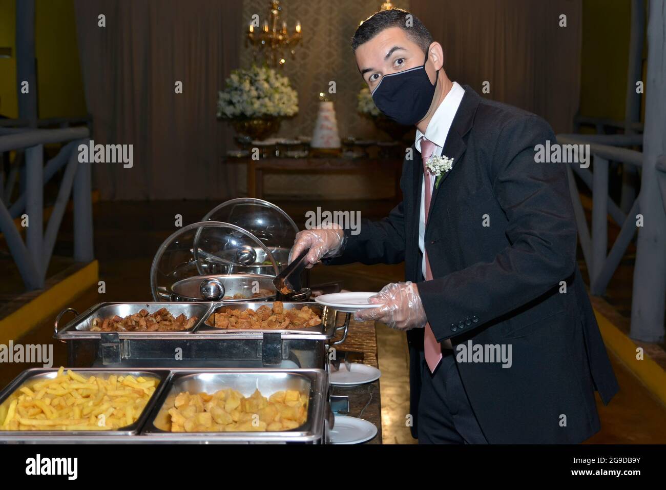 adult male wearing respiratory mask and gloves, serving at buffet ...