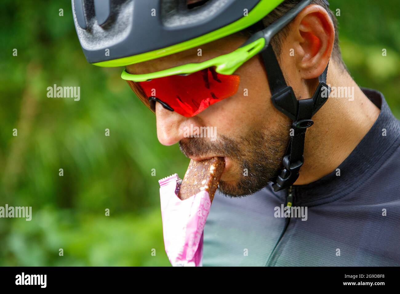 Athletic caucasian man eats protein on bicycle in nature. Young ...