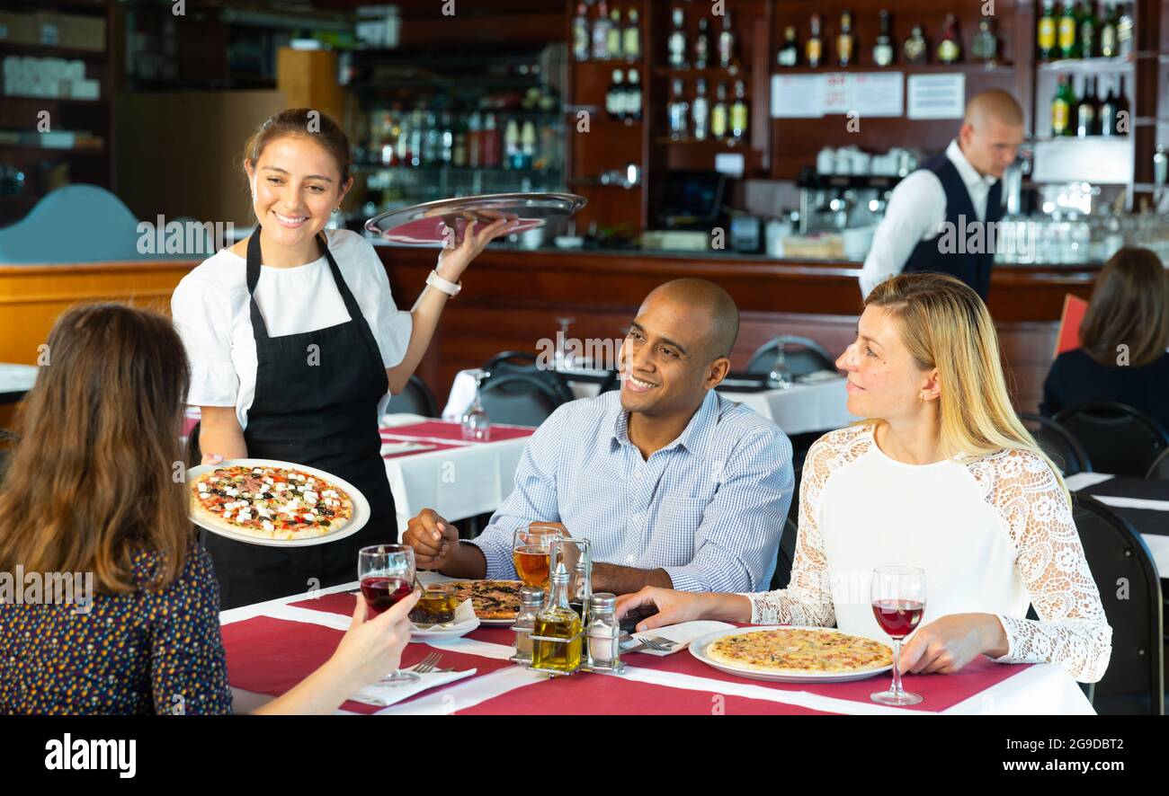 Smiling waitress serving pizza hi-res stock photography and images - Alamy