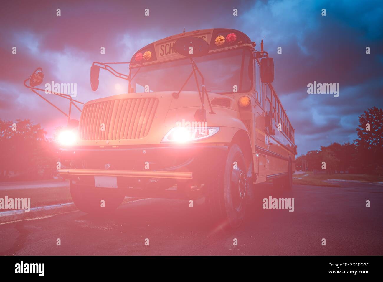 Low angle front view of yellow American public school bus a night with ...