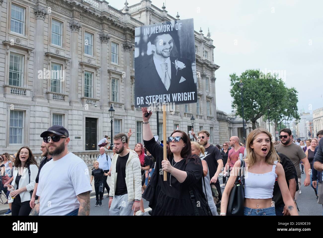 Dr Stephen Wright's widow holds up a placard bearing his photograph at ...
