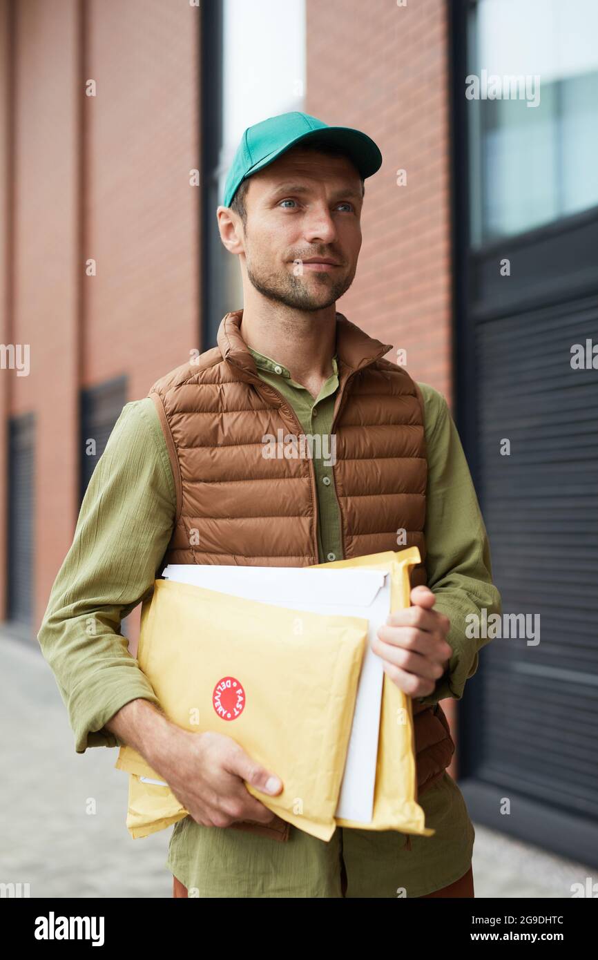 Vertical waist up portrait of delivery man holding parcels and looking ...
