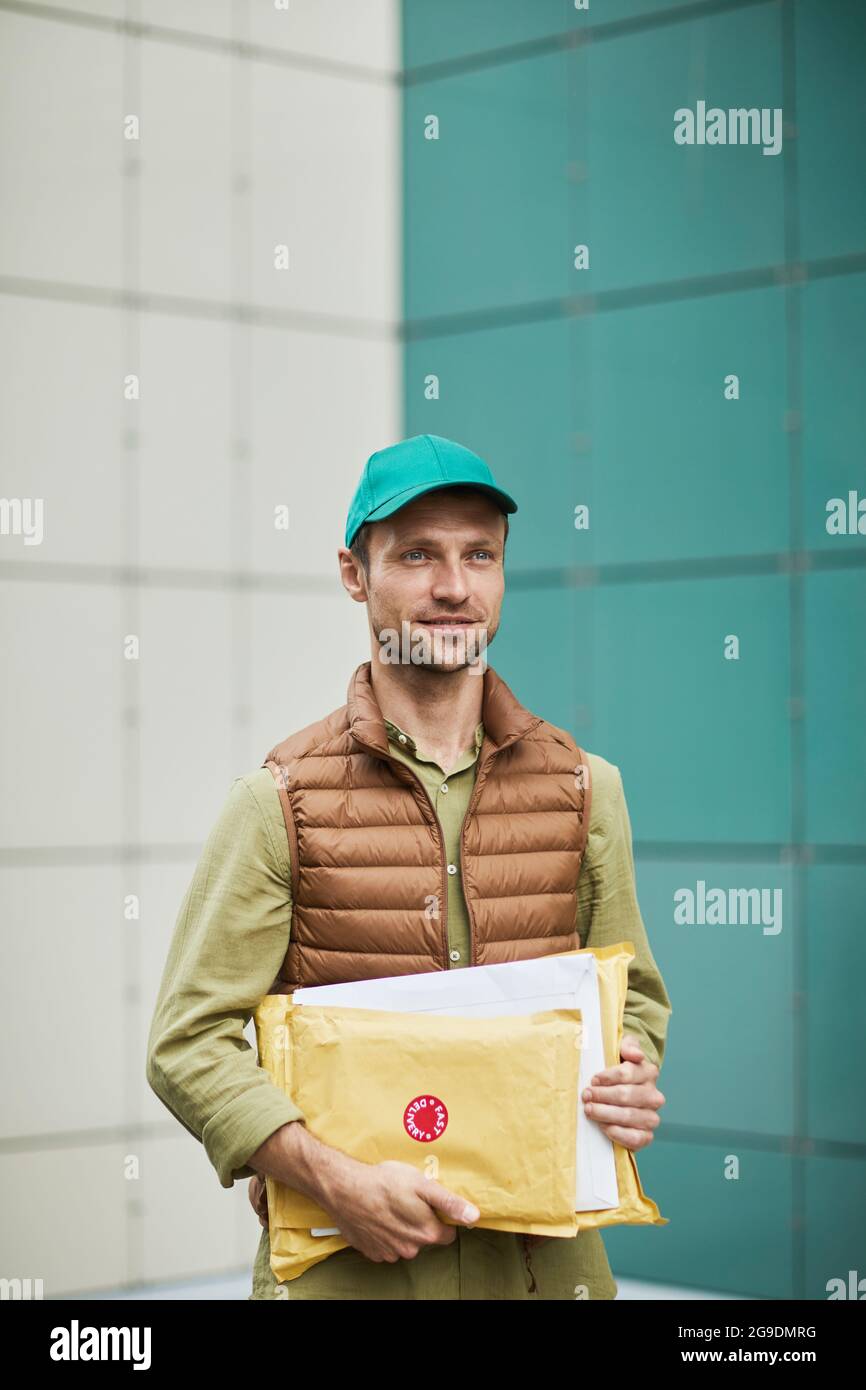 Vertical waist up portrait of delivery man holding parcels and smiling ...