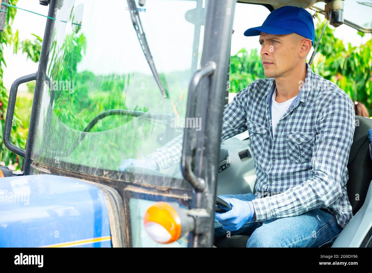 Professional farmer sitting in a tractor at a orchard Stock Photo - Alamy
