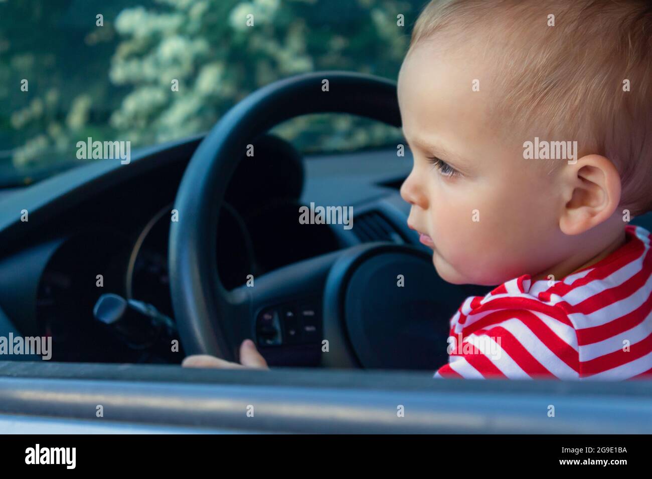 Boy sitting behind car wheel. Safety concept Stock Photo - Alamy