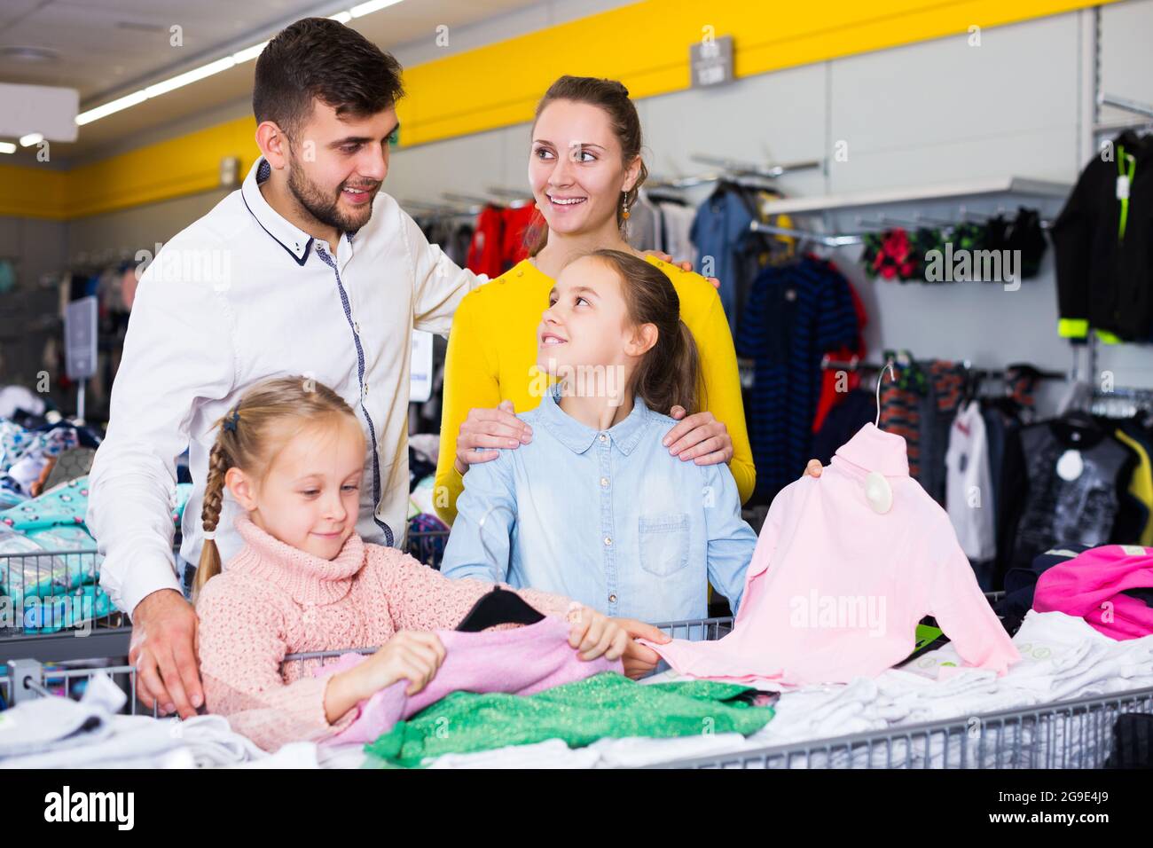 family with two girls choosing new clothes Stock Photo - Alamy