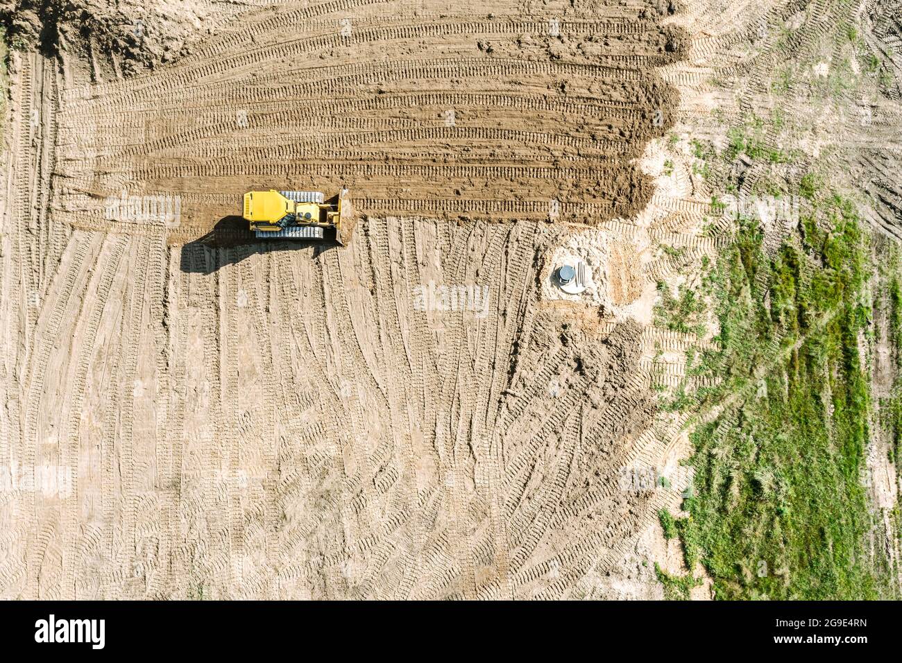 yellow bulldozer leveling the ground before construction works. aerial ...