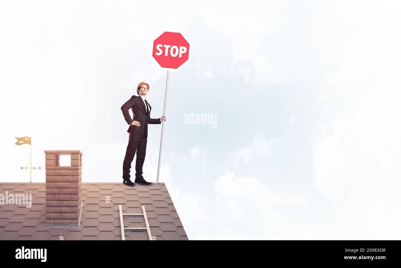 Caucasian businessman on brick house roof showing stop road sign Stock ...