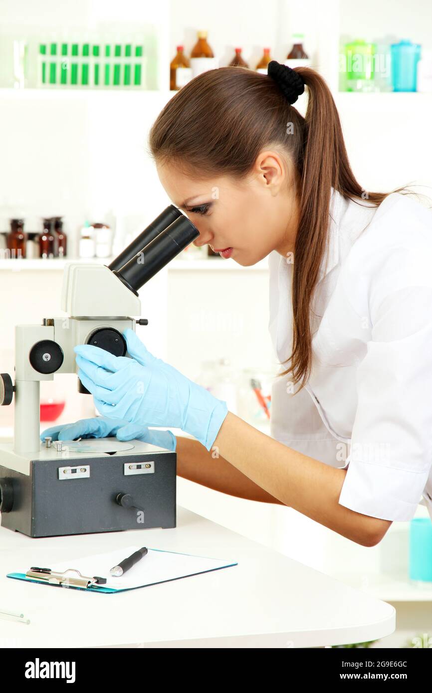 Young scientist looking into microscope in laboratory Stock Photo - Alamy