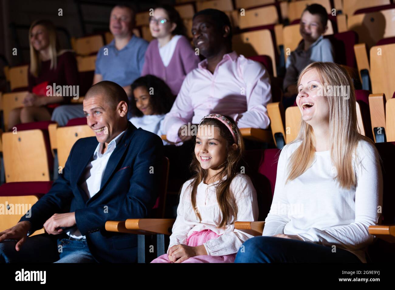 Cheerful parents with tween daughter watching theatrical performance ...