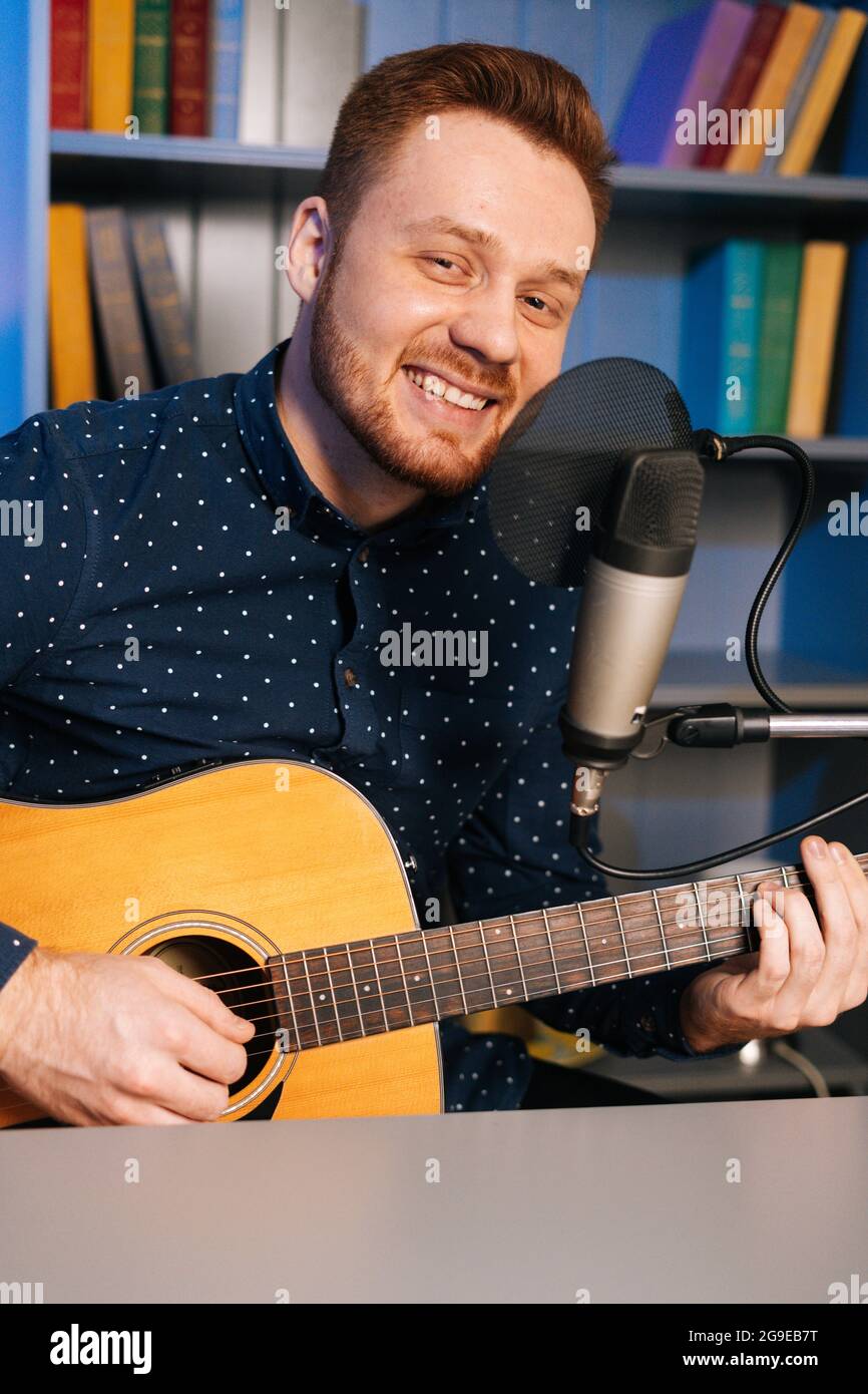 Vertical portrait of cheerful guitarist singer man playing on acoustic ...
