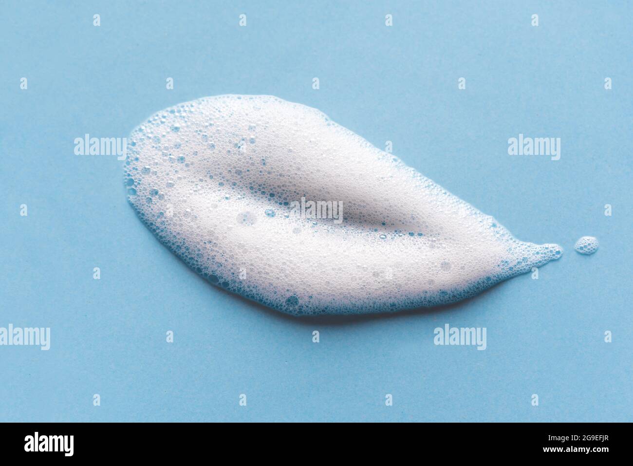 Face cleansing mousse sample. White cleanser foam bubbles on blue ...