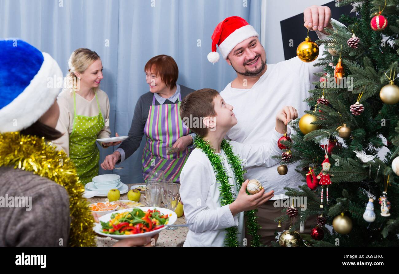 Family decorating Christmas tree and setting table Stock Photo - Alamy