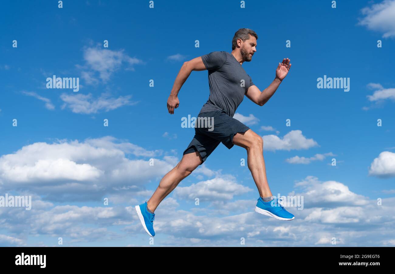 sportsman with muscular body running in sportswear outdoor on sky ...