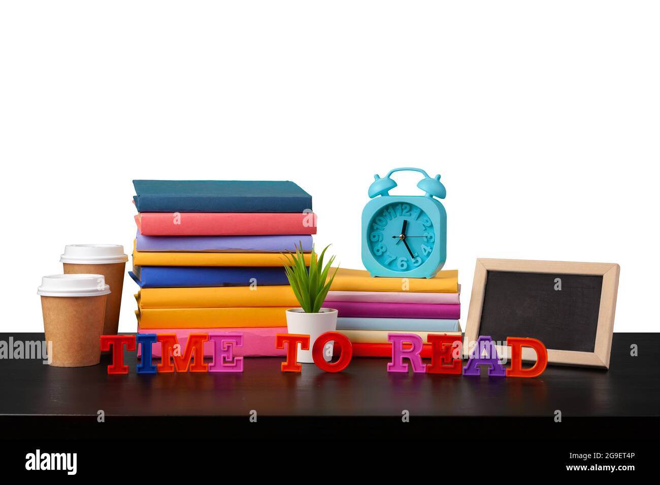 Alarm clock, stack of books and cup on tabletop against white ...