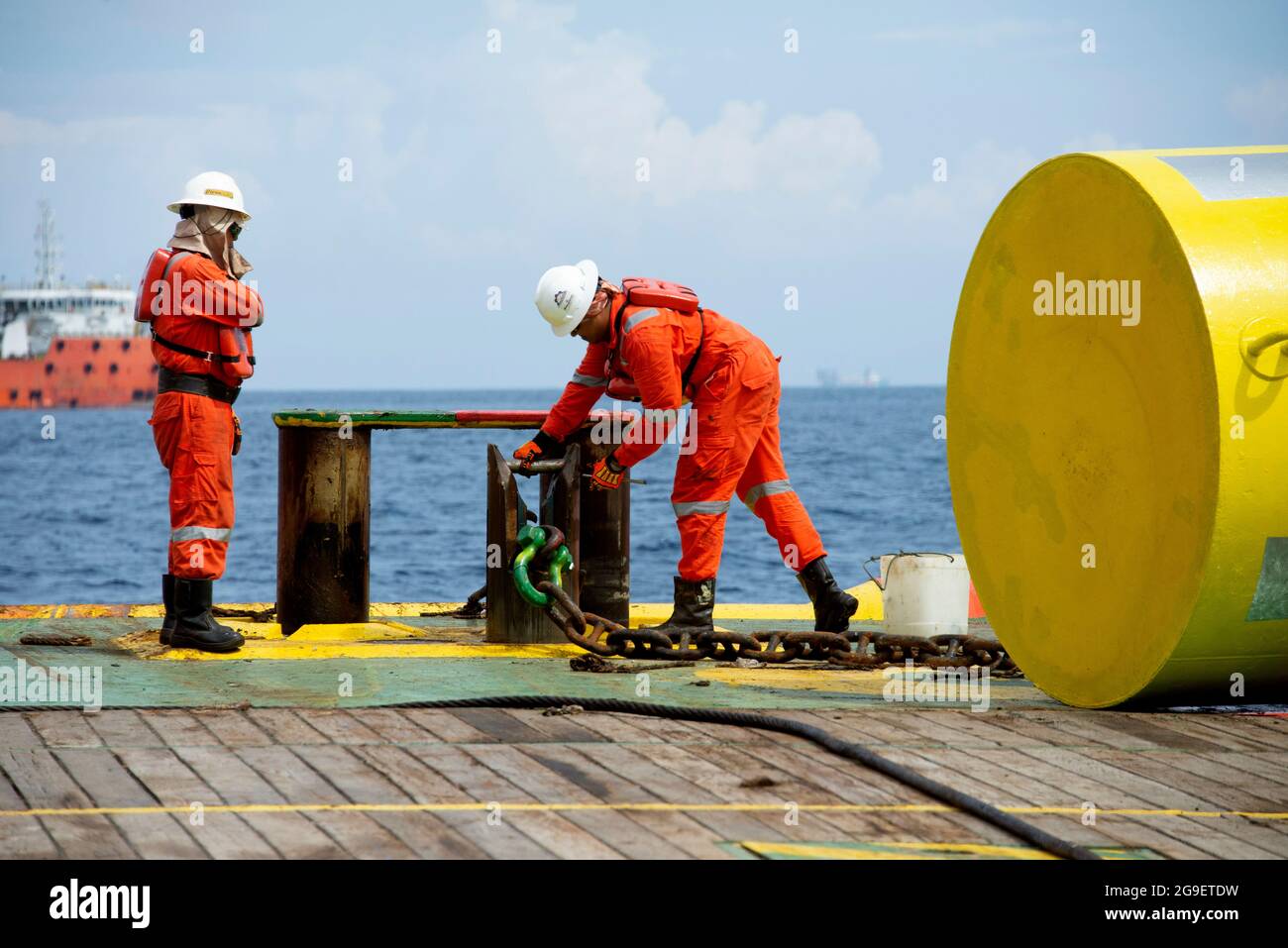 marine crew working on deck during anchor handling operation at sea ...