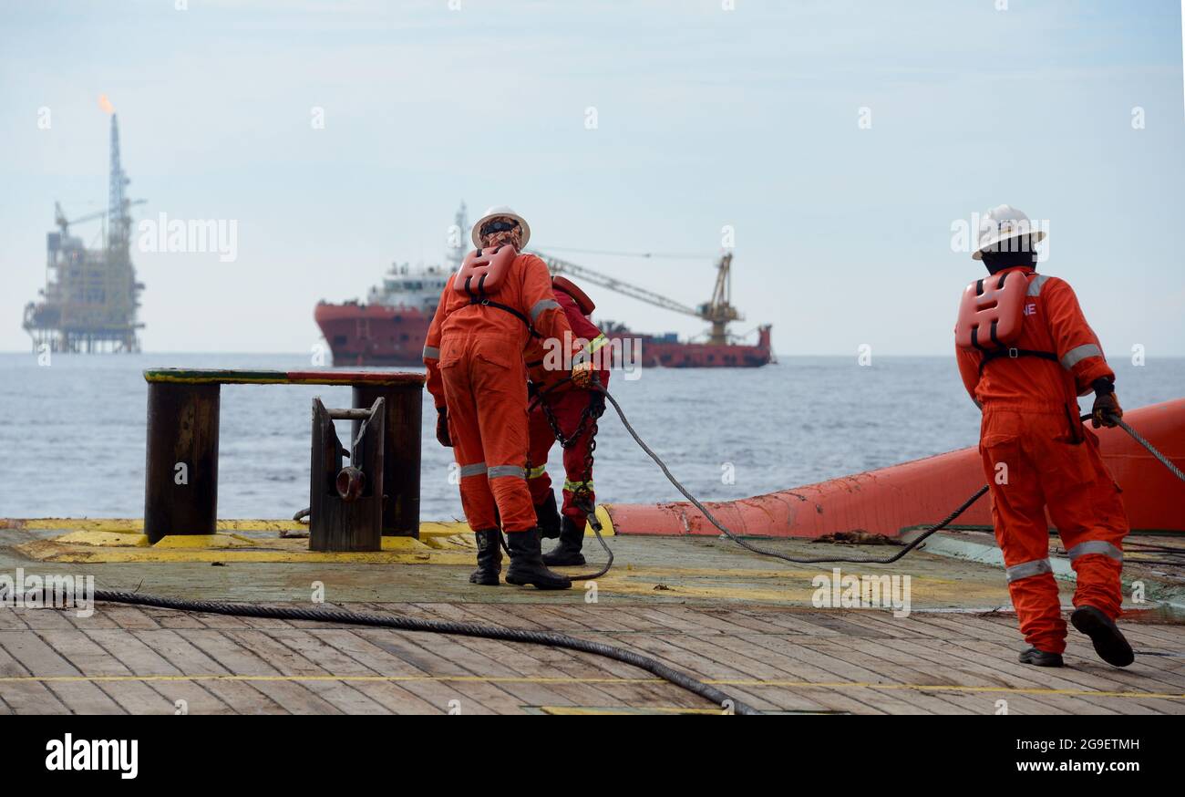 marine crew working on deck during anchor handling operation at sea ...