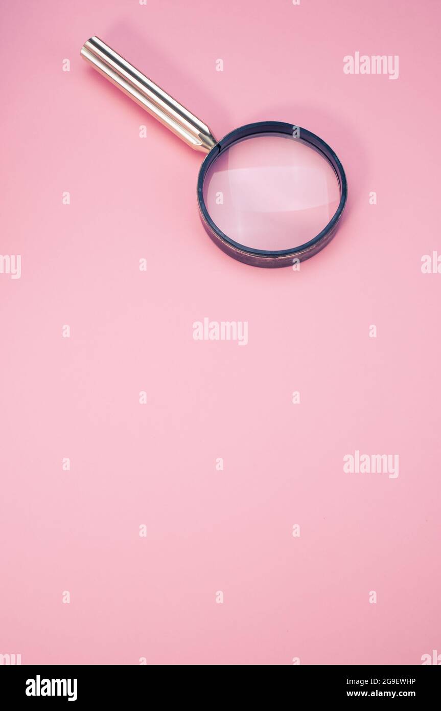 Vertical closeup of a magnifier on pink background Stock Photo - Alamy