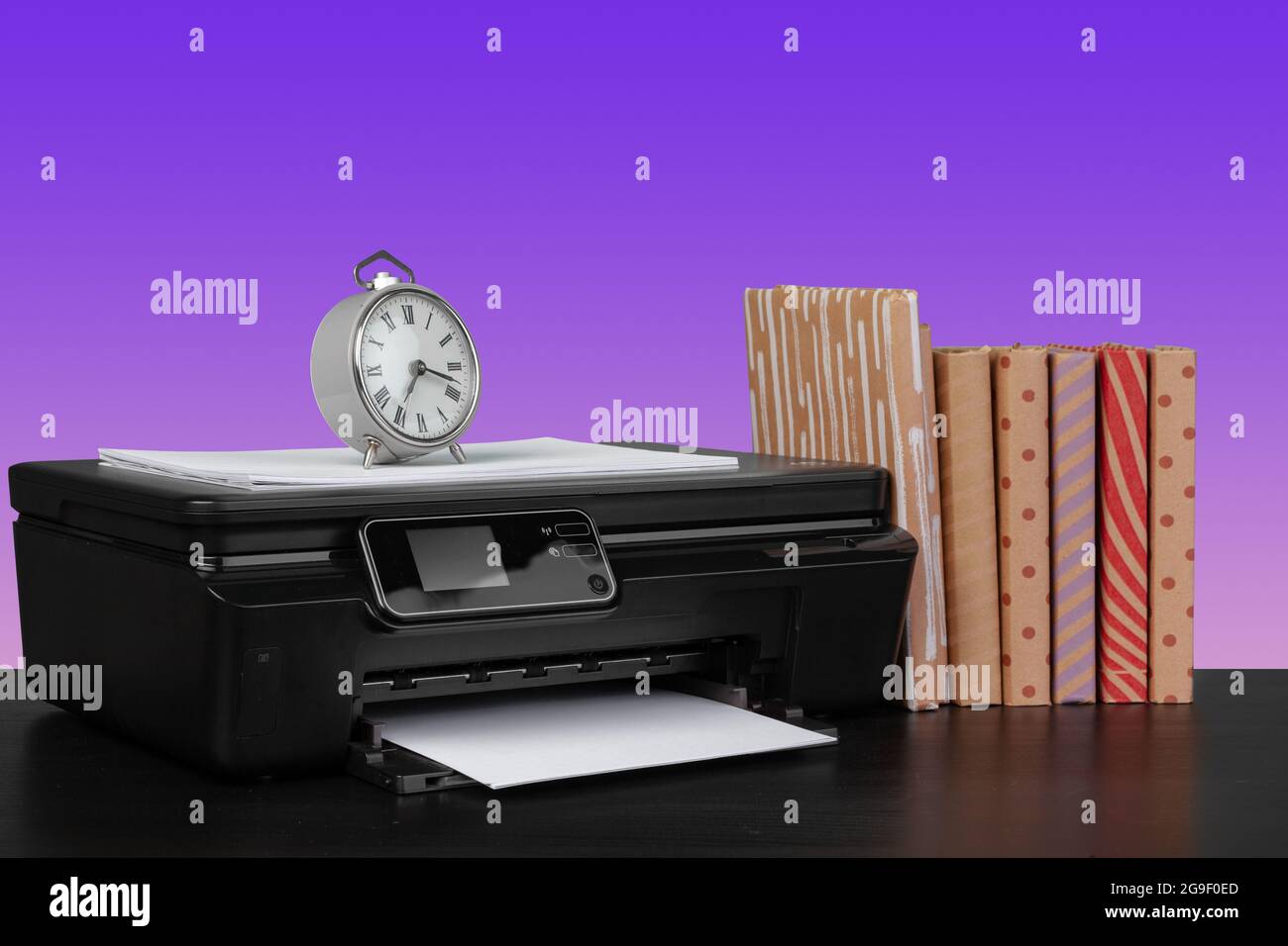 Home laser printer on desk against purple background Stock Photo - Alamy