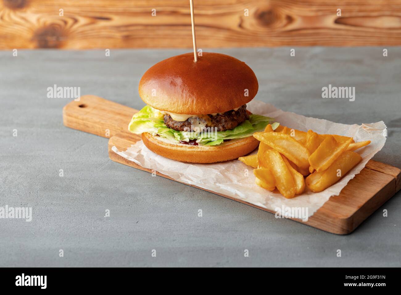 Fresh burger and potato wedges on gray wooden background Stock Photo ...