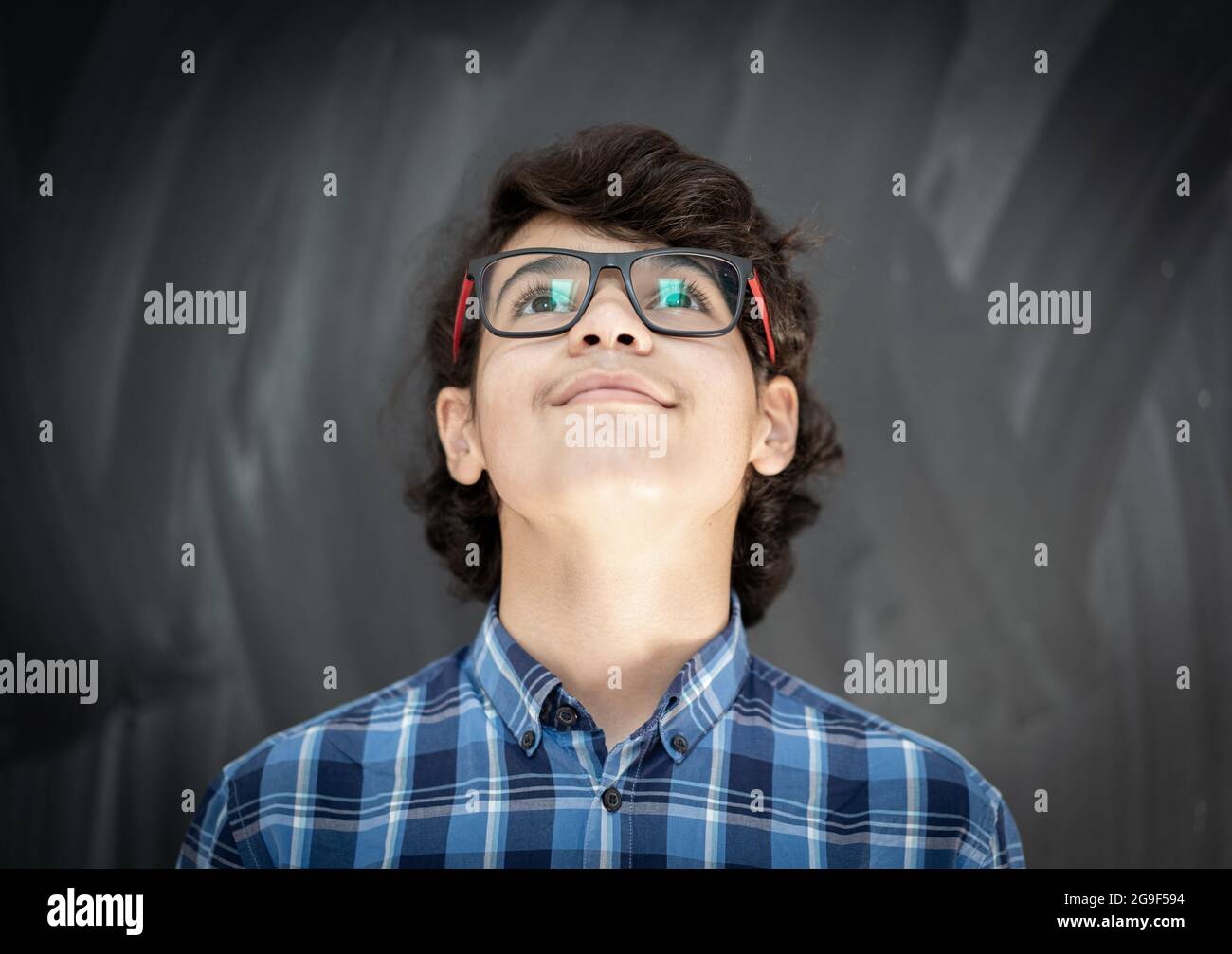 Teenage boy with glasses in front of classroom chalkboard Stock Photo ...