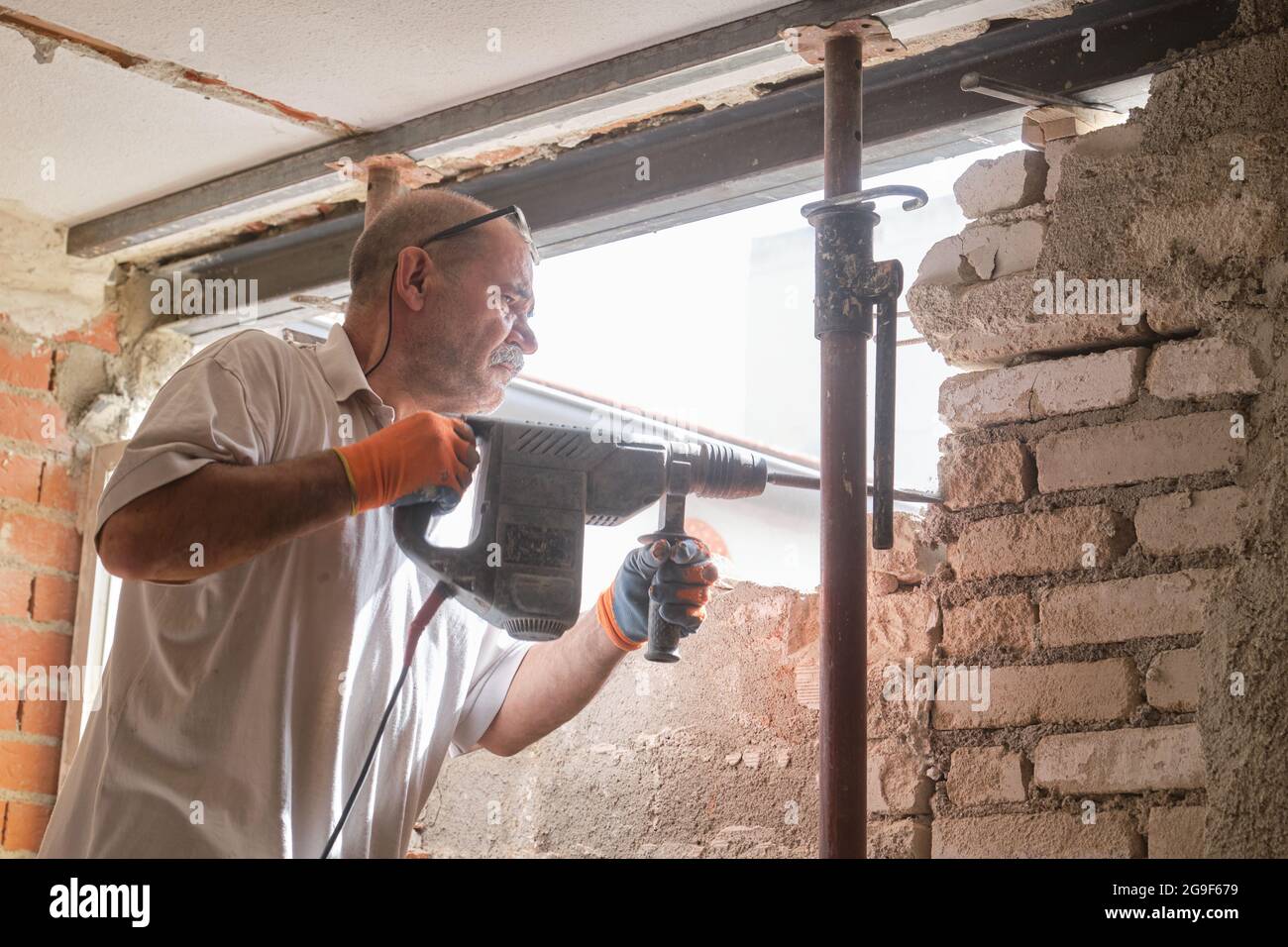Construction worker with demolition jackhammer breaking an interior ...