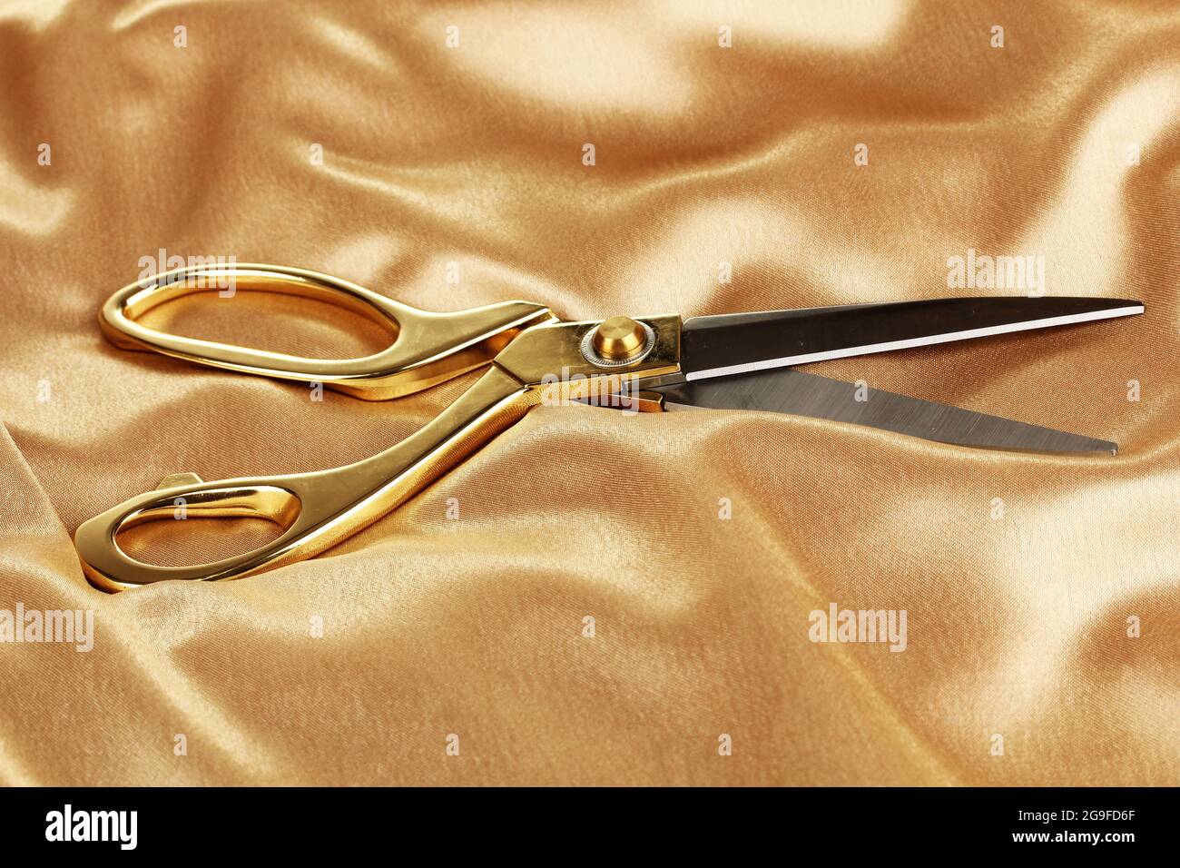 Metal scissors on gold fabric Stock Photo - Alamy