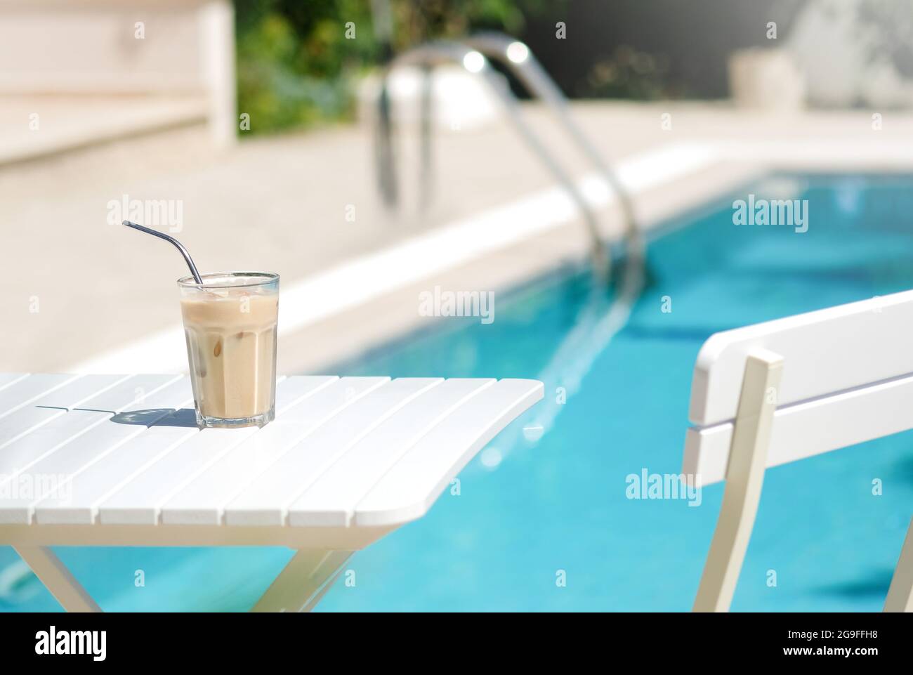Ice coffee Cyprus Frappe Fredo against blue clear water of the swimming ...
