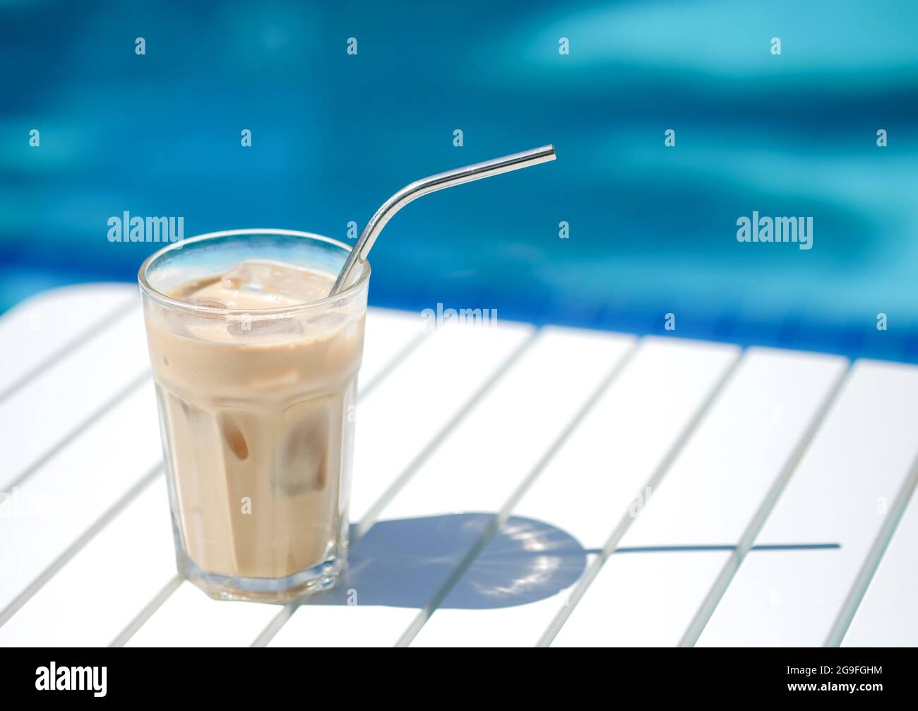 Ice coffee Cyprus Frappe Fredo against blue clear water of the swimming ...