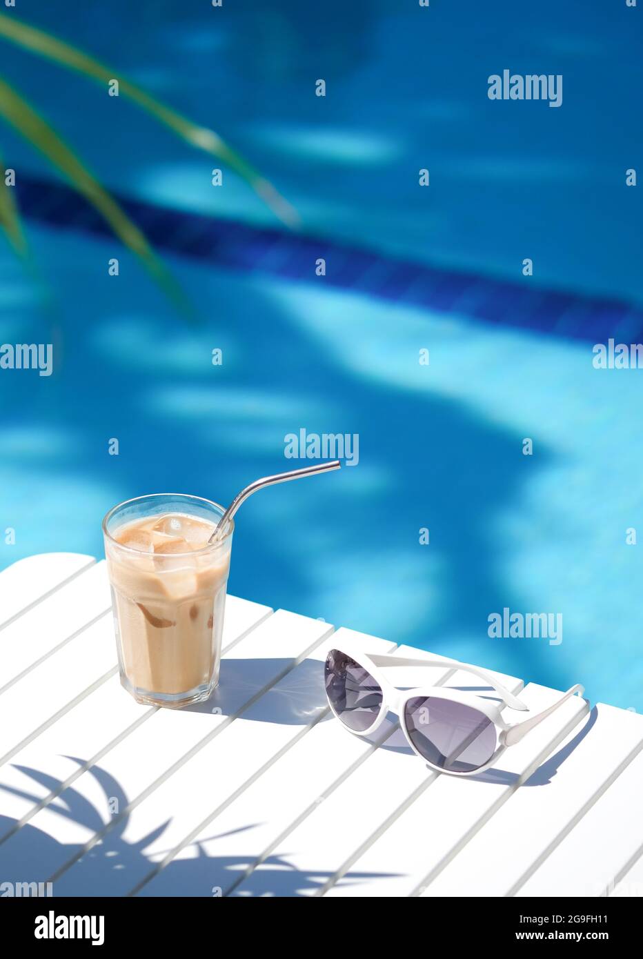 Ice coffee Cyprus Frappe Fredo against blue clear water of the swimming ...