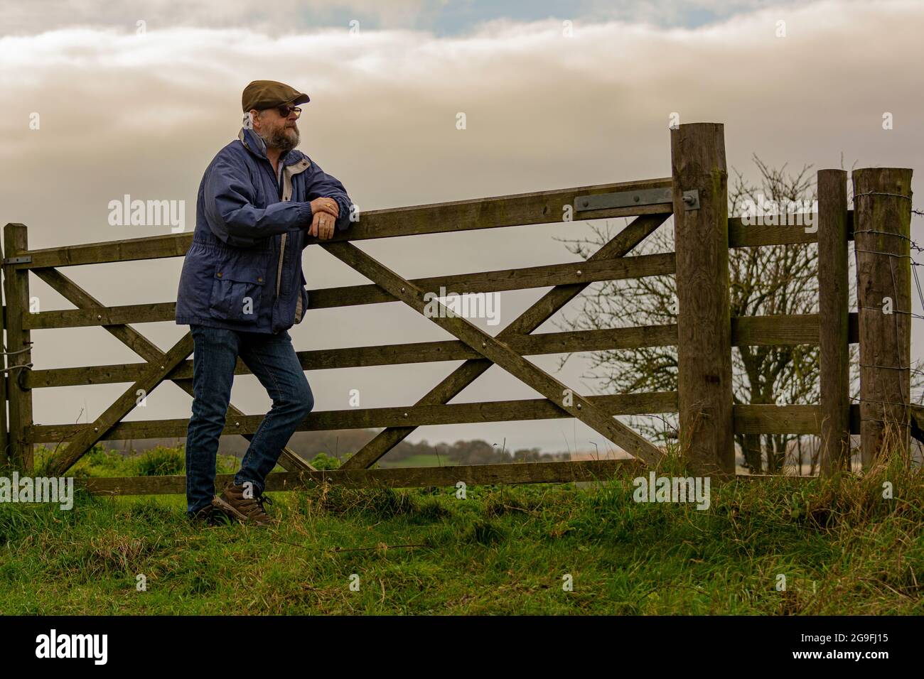 Aged male standing, staring by a 5 barred gate Stock Photo - Alamy