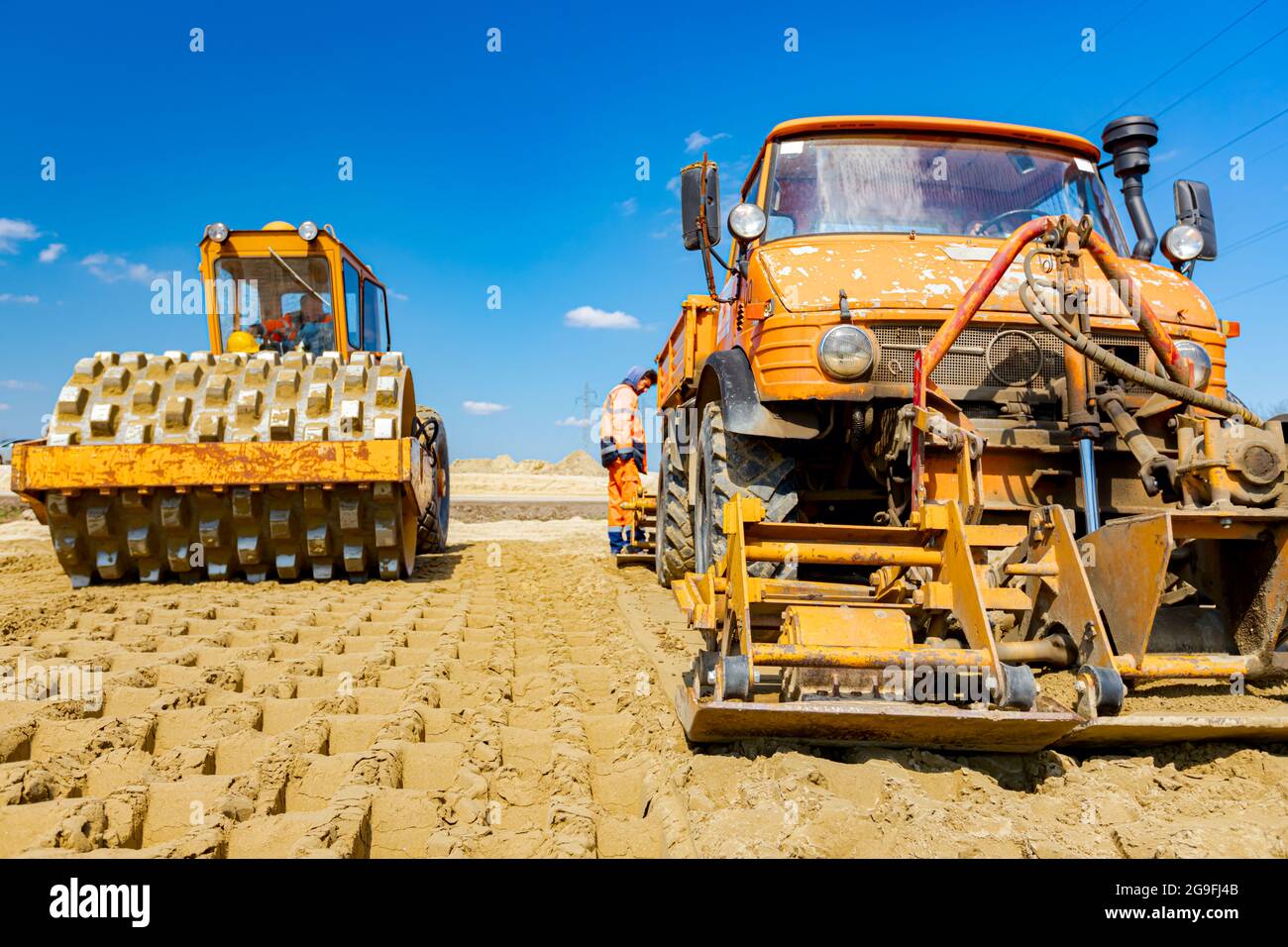 Road roller with spikes and truck with mounted plate vibration ...
