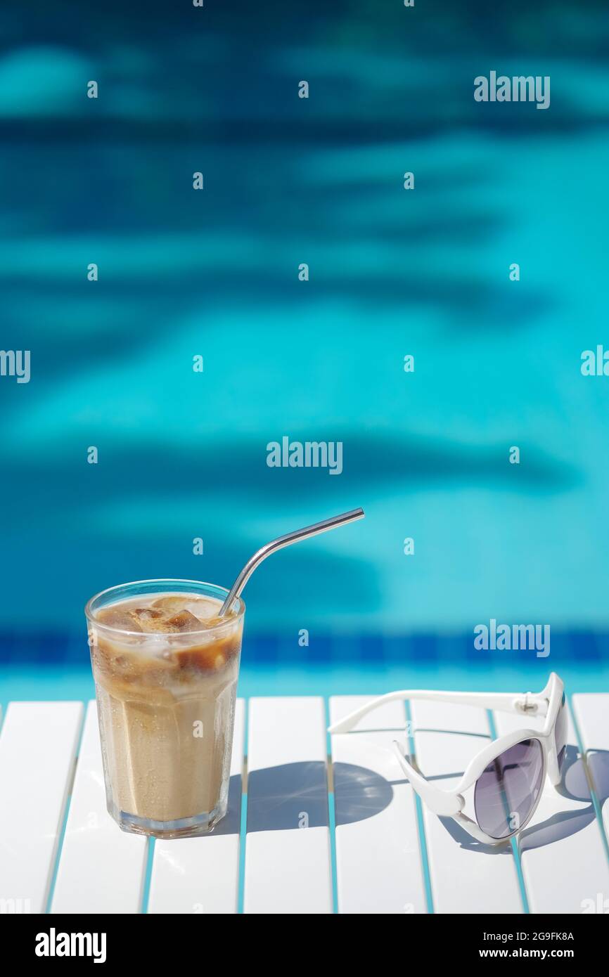 Ice coffee Cyprus Frappe Fredo against blue clear water of the swimming ...
