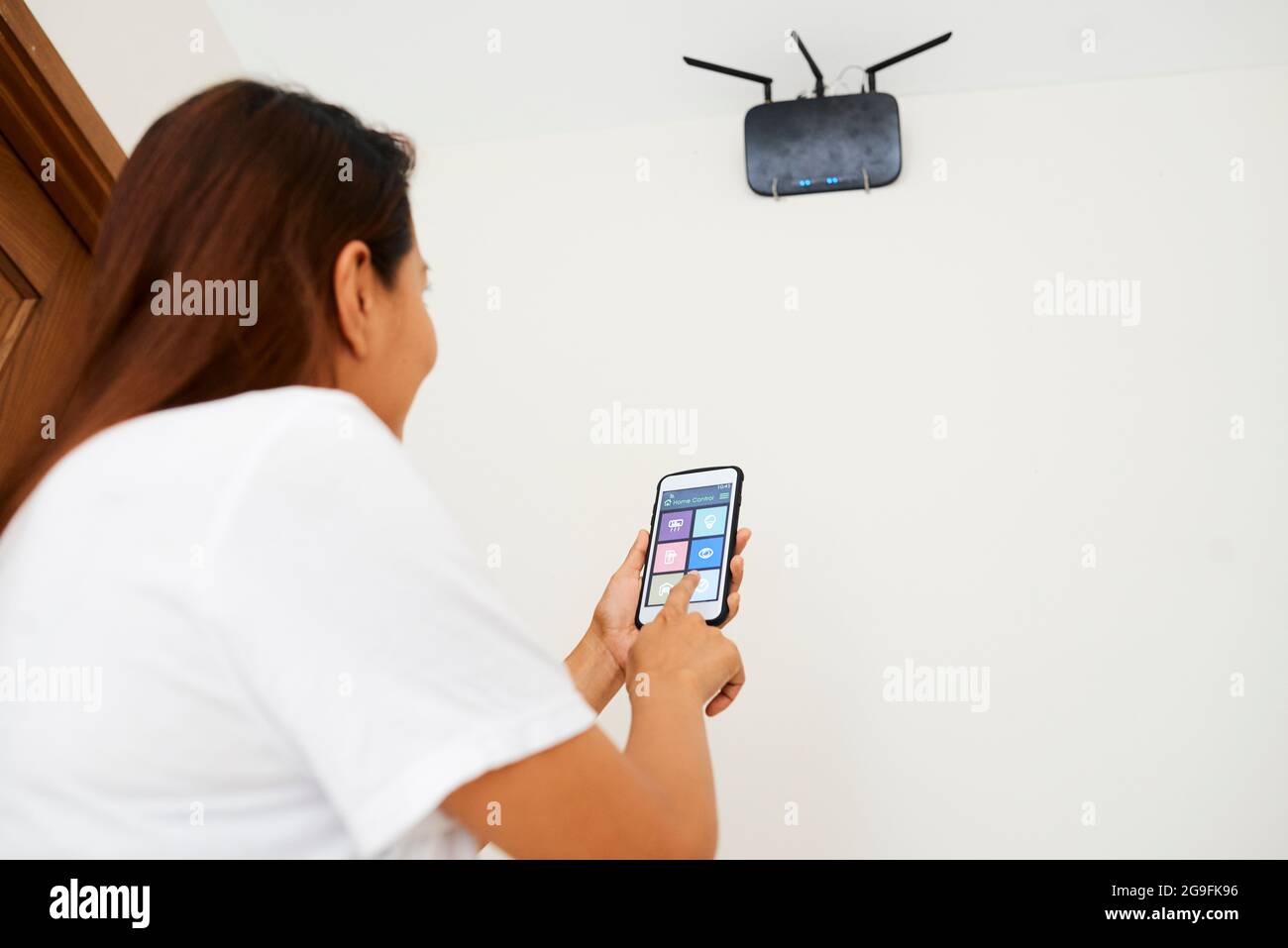Housewife setting wi-fi router hanging on wall via application on ...