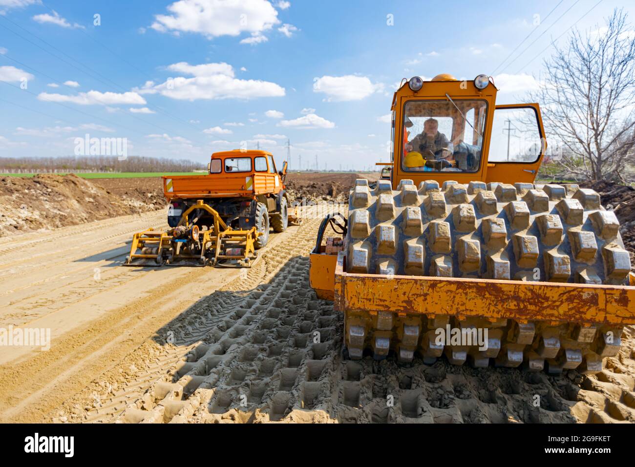 Road roller with spikes and truck with mounted plate vibration ...