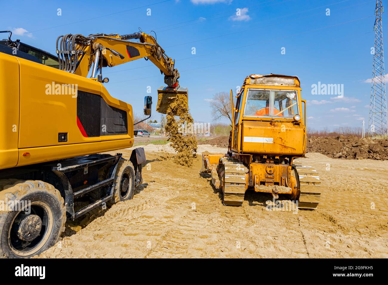 View from behind on bulldozer and excavator that are leveling sand for ...