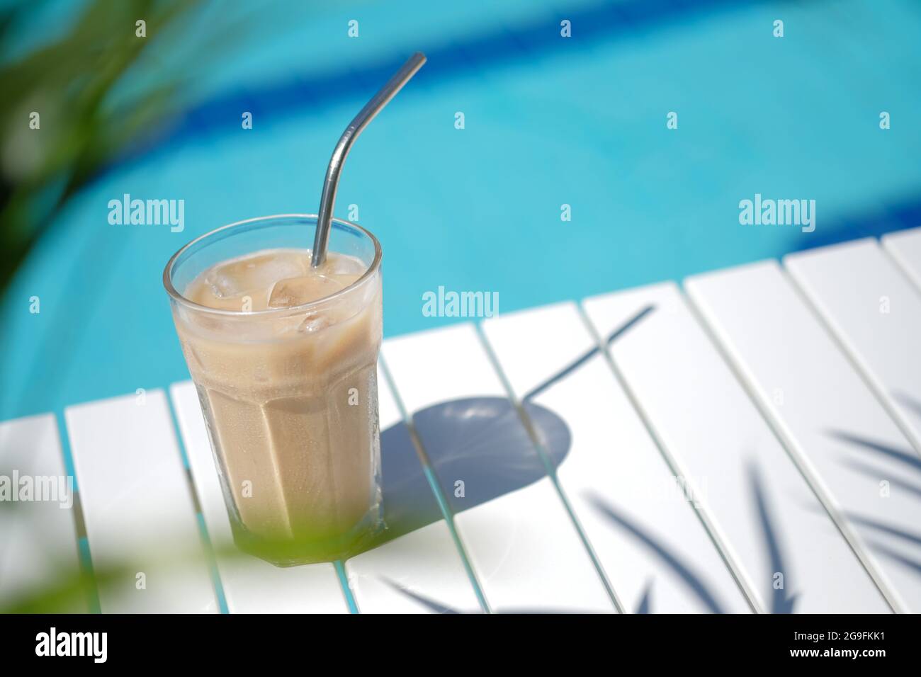Ice coffee Cyprus Frappe Fredo against blue clear water of the swimming ...