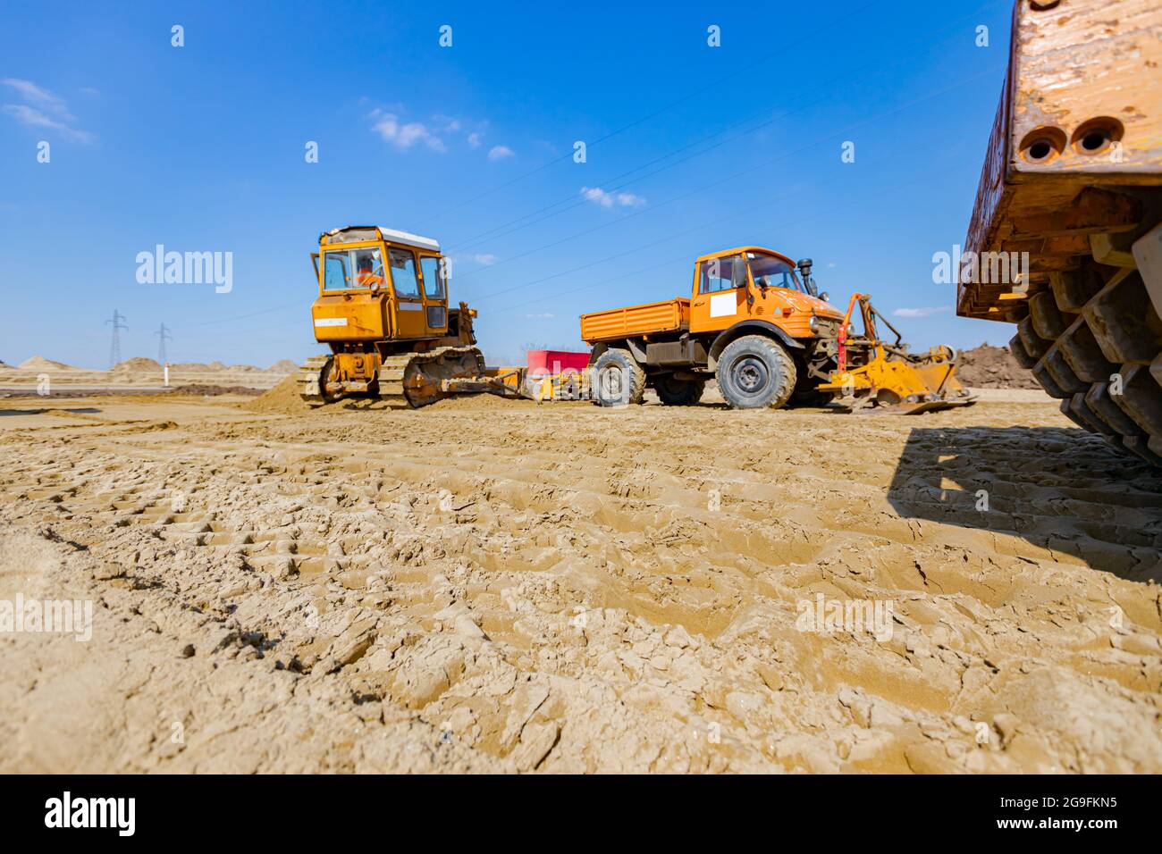 View over roller with spikes on bulldozer and excavators are leveling ...