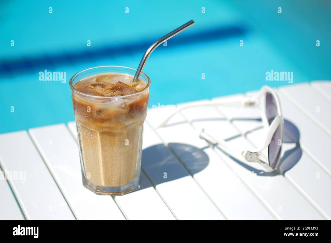 Ice coffee Cyprus Frappe Fredo against blue clear water of the swimming ...