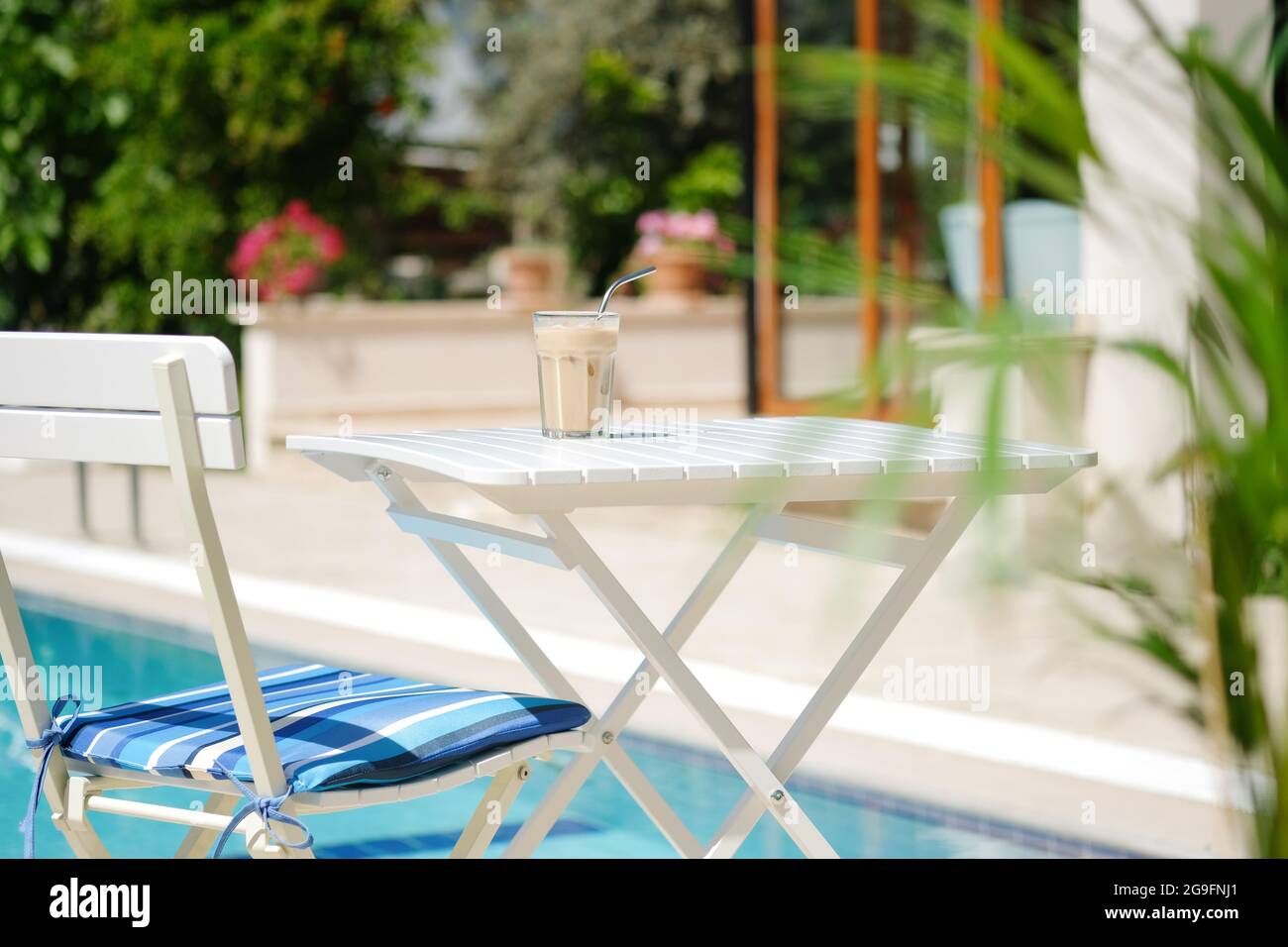 Ice coffee Cyprus Frappe Fredo against blue clear water of the swimming ...