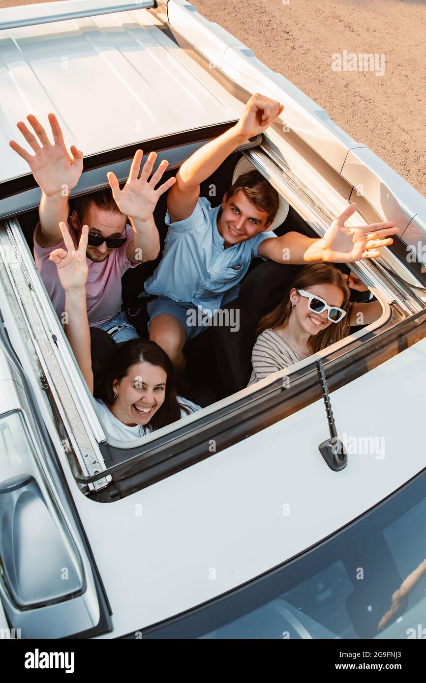 group of friends in car looking up through sunroof. road trip ...