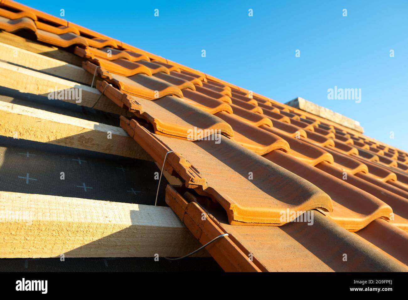 Overlapping rows of yellow ceramic roofing tiles mounted on wooden ...