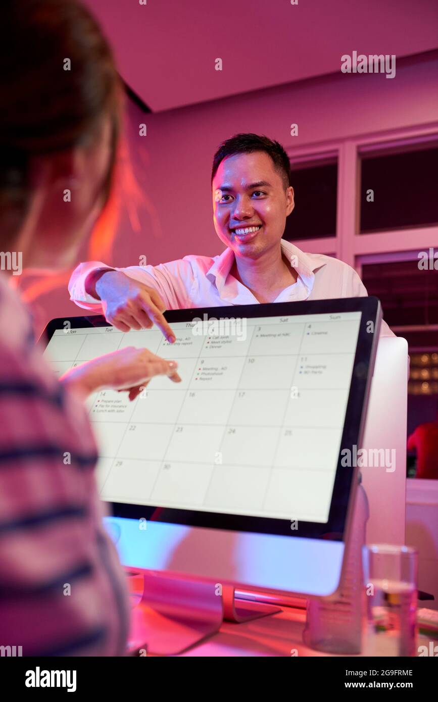 Smiling business team planning meeting and choosing date and time in calendar on computer screen ...