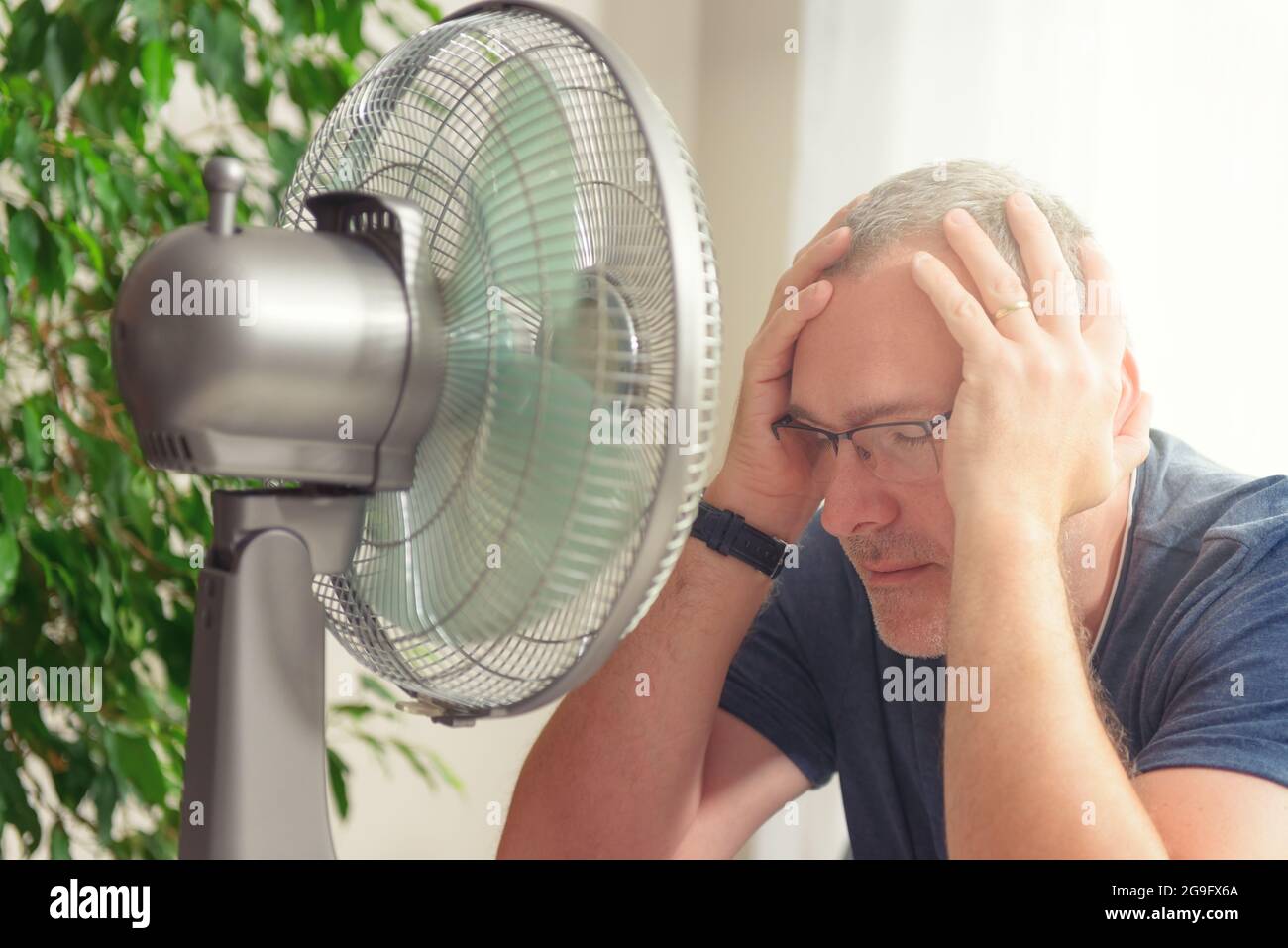 Man suffers from heat at home and tries to cool off by the fan Stock ...