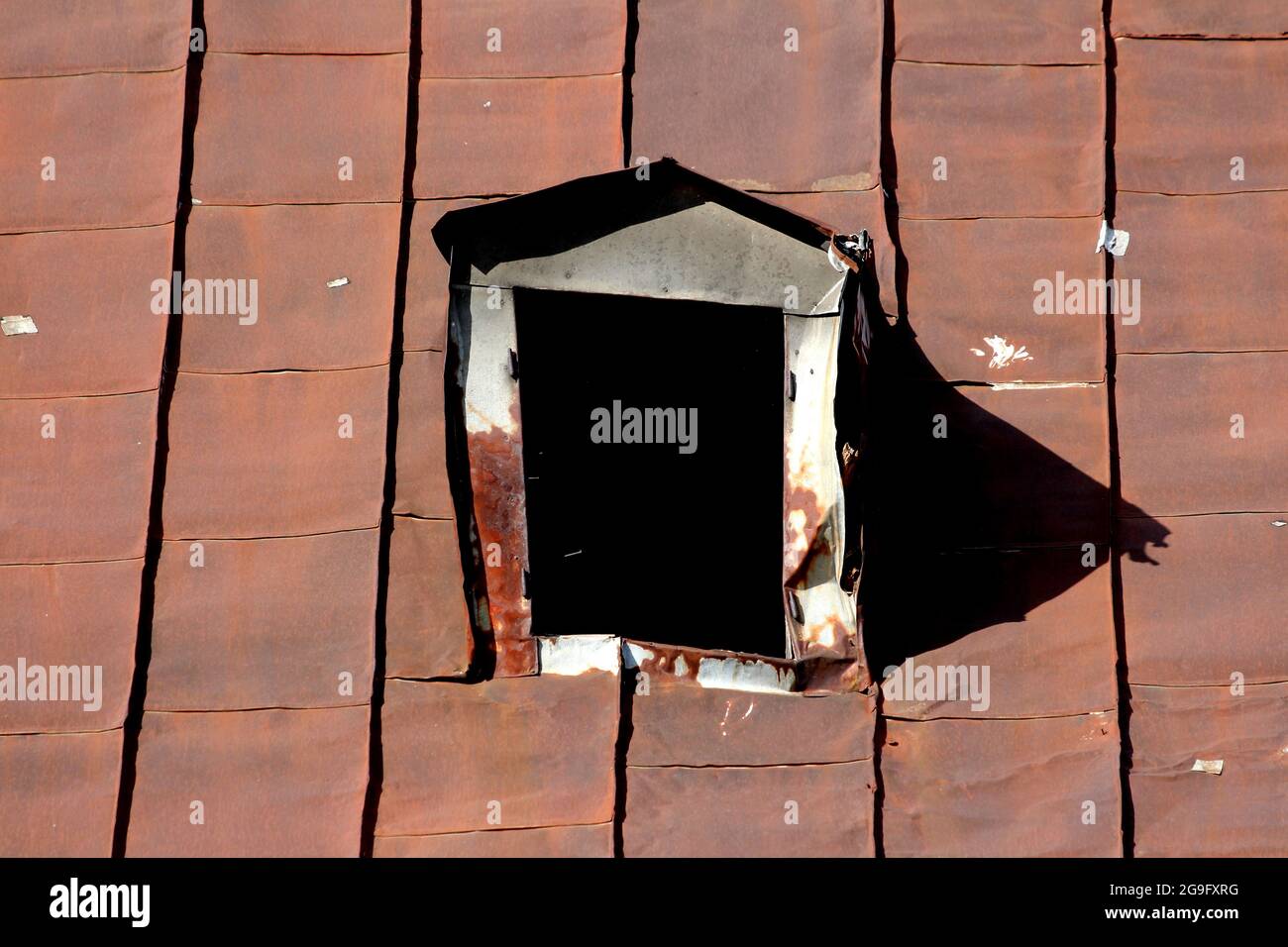 Twisted damaged broken old roof window frame without glass on top of abandoned suburban family ...