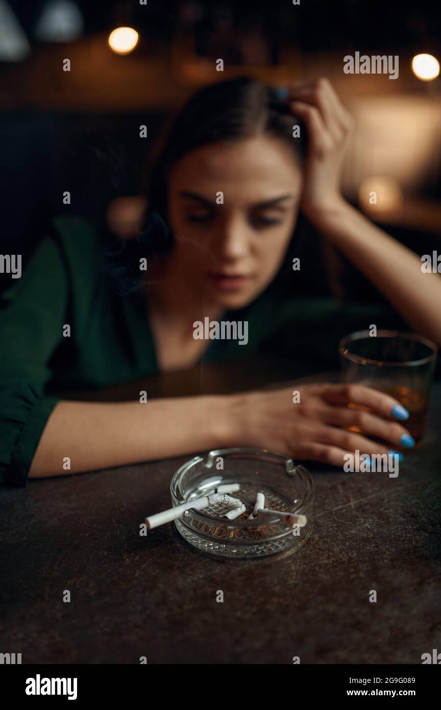 Drunk woman smokes a cigarette at counter in bar Stock Photo - Alamy