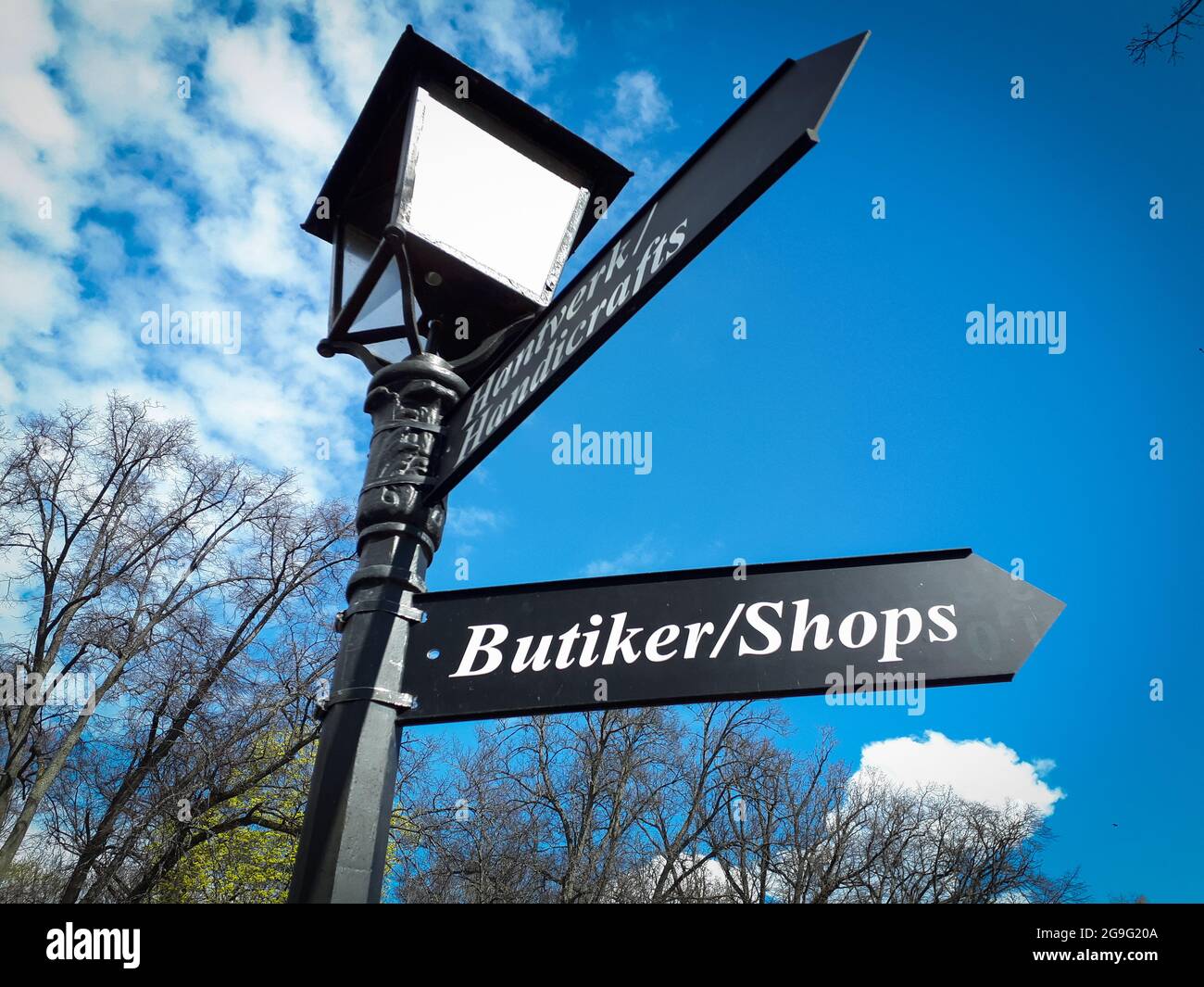 Low angle shot of a street light with a sign leading to shops Stock ...