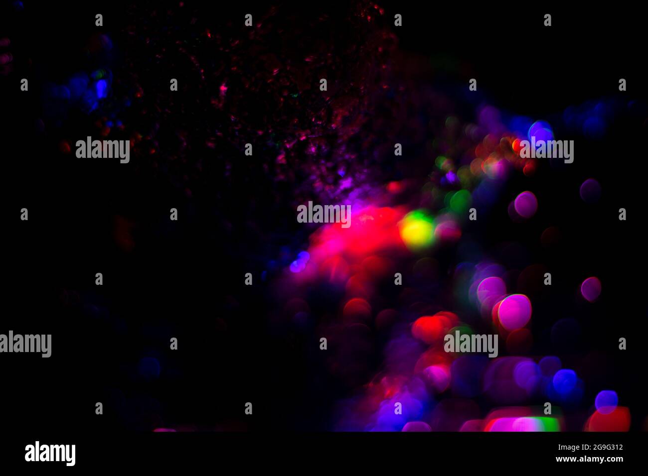 Colored water texture. Splashes of water lit in different colors. Close ...