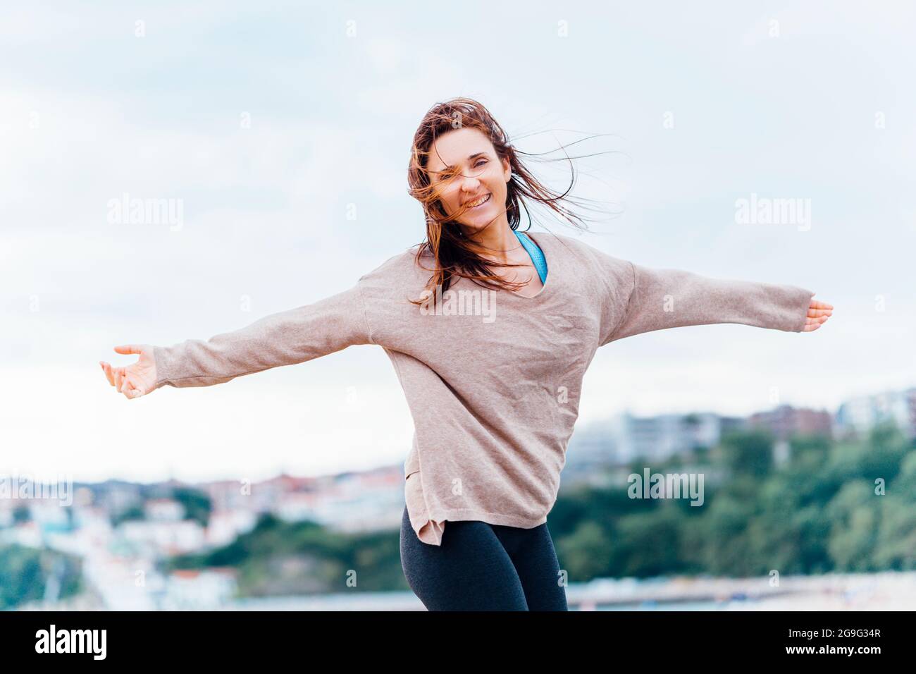 beautiful young adult woman with open arms smiling with feeling of ...
