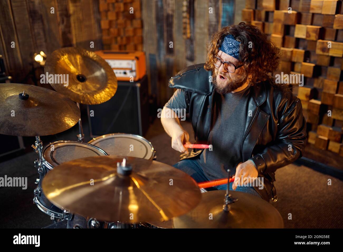 Brutal musician behind the drum kit on stage Stock Photo - Alamy